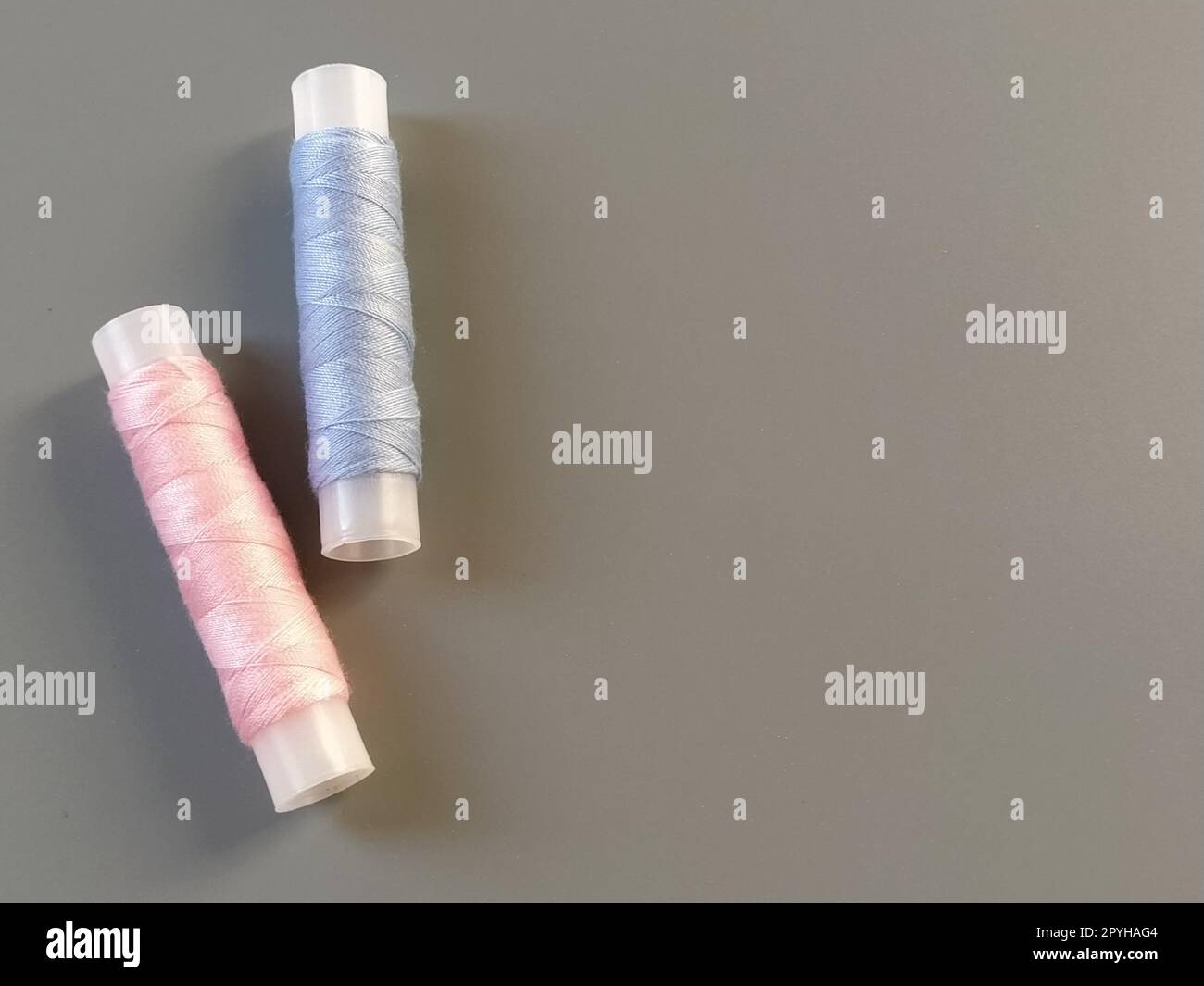 Spools of pink and blue thread on a gray background. Textile industry ...