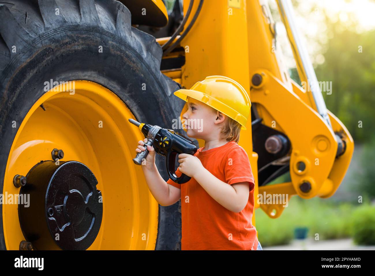 Little boy with toy tools in garage. Son helps father to repair tractor ...
