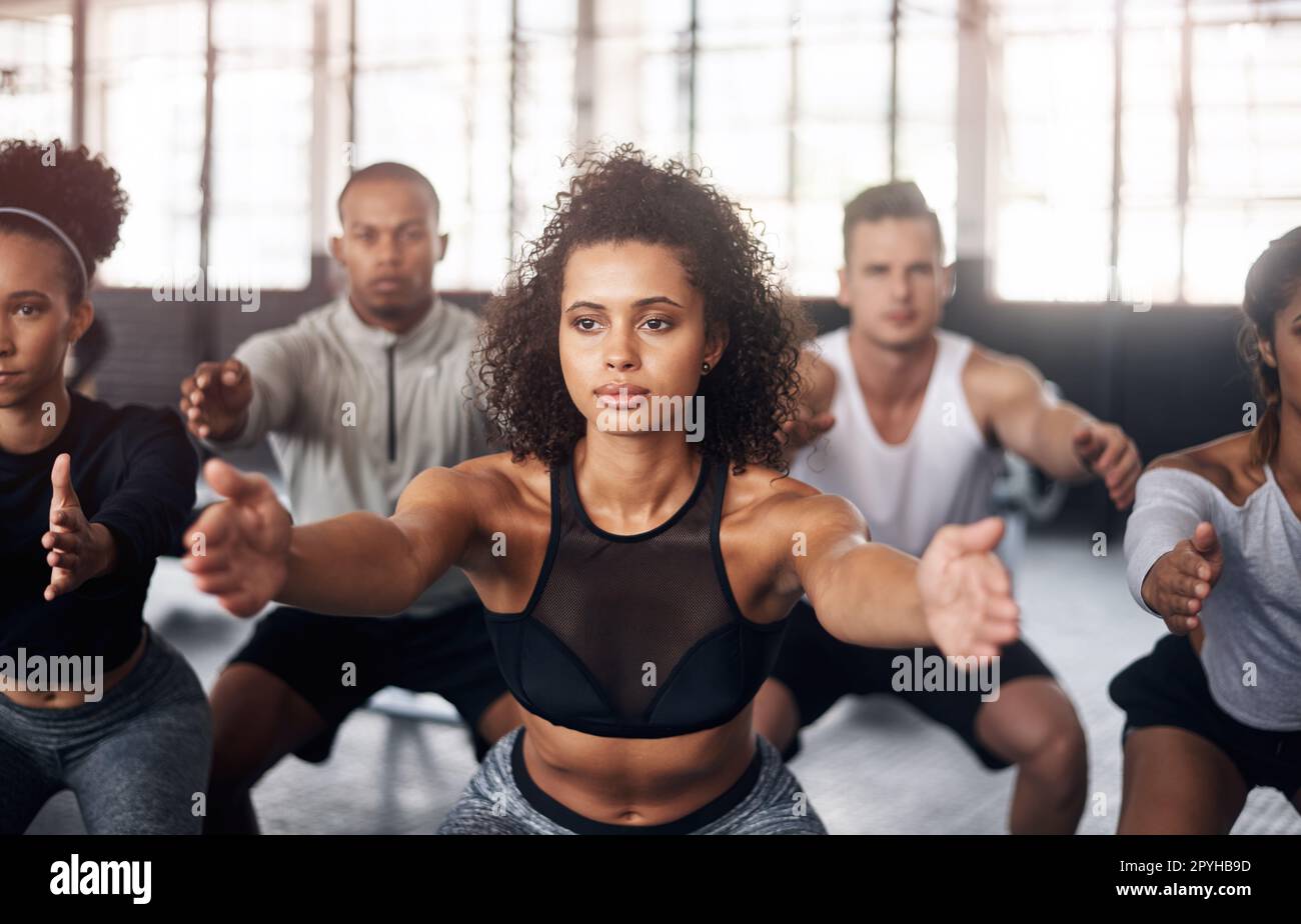 Strong glutes activated. a group of young people doing squats together ...