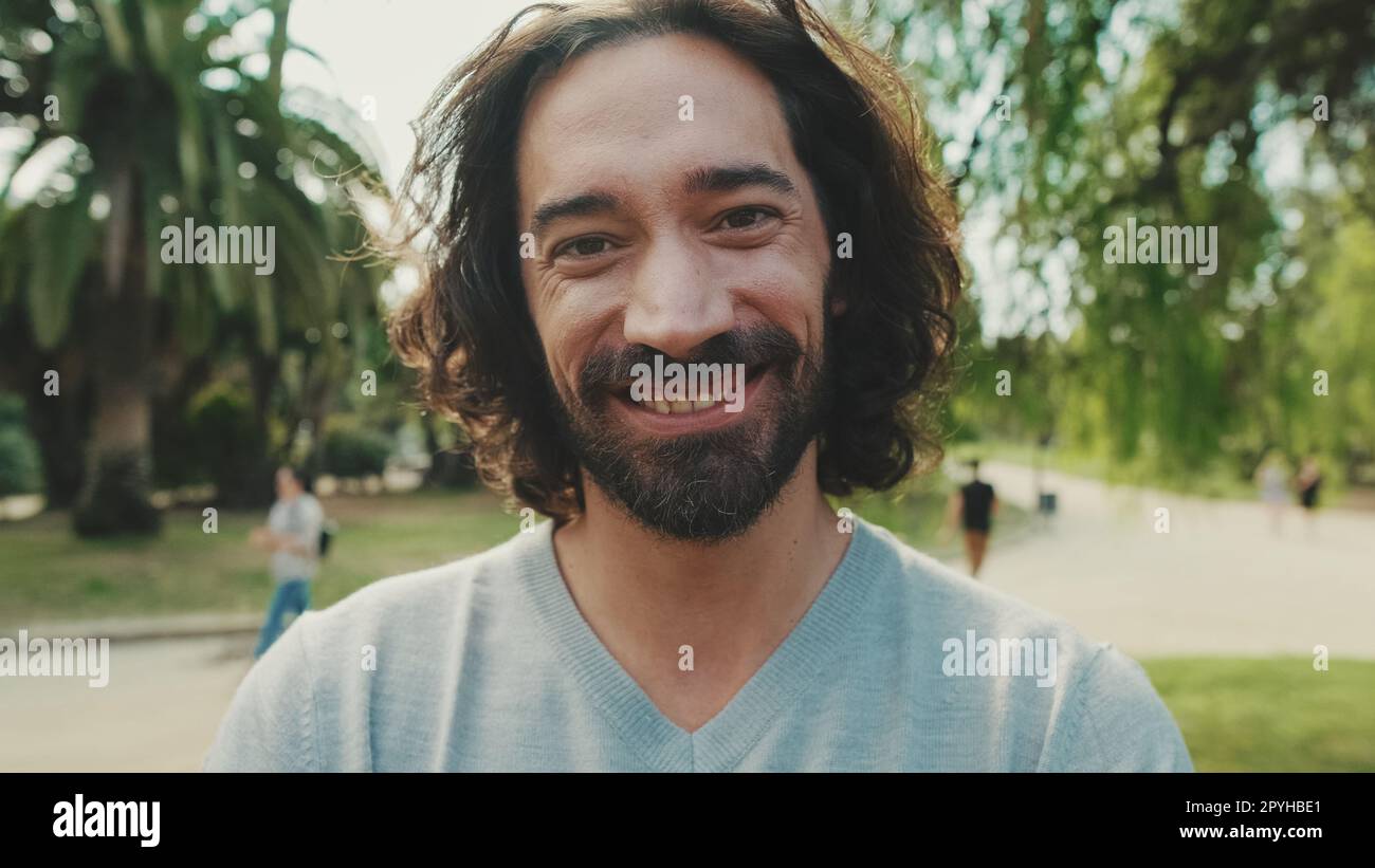 Close up, young man raises his head, looks at the camera and smiles ...