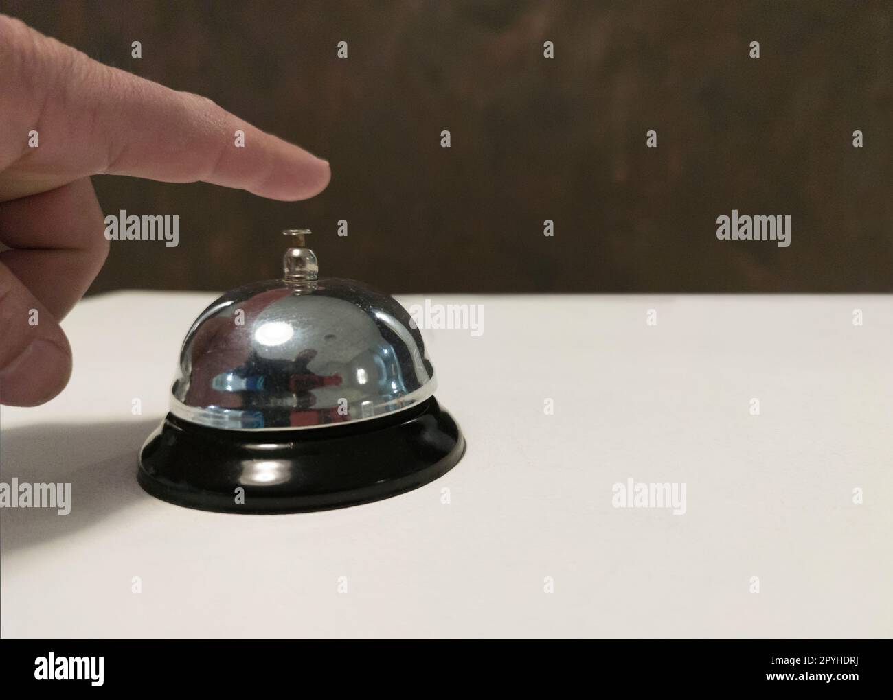 Guest about to press the service bell at the hotel reception. White ...