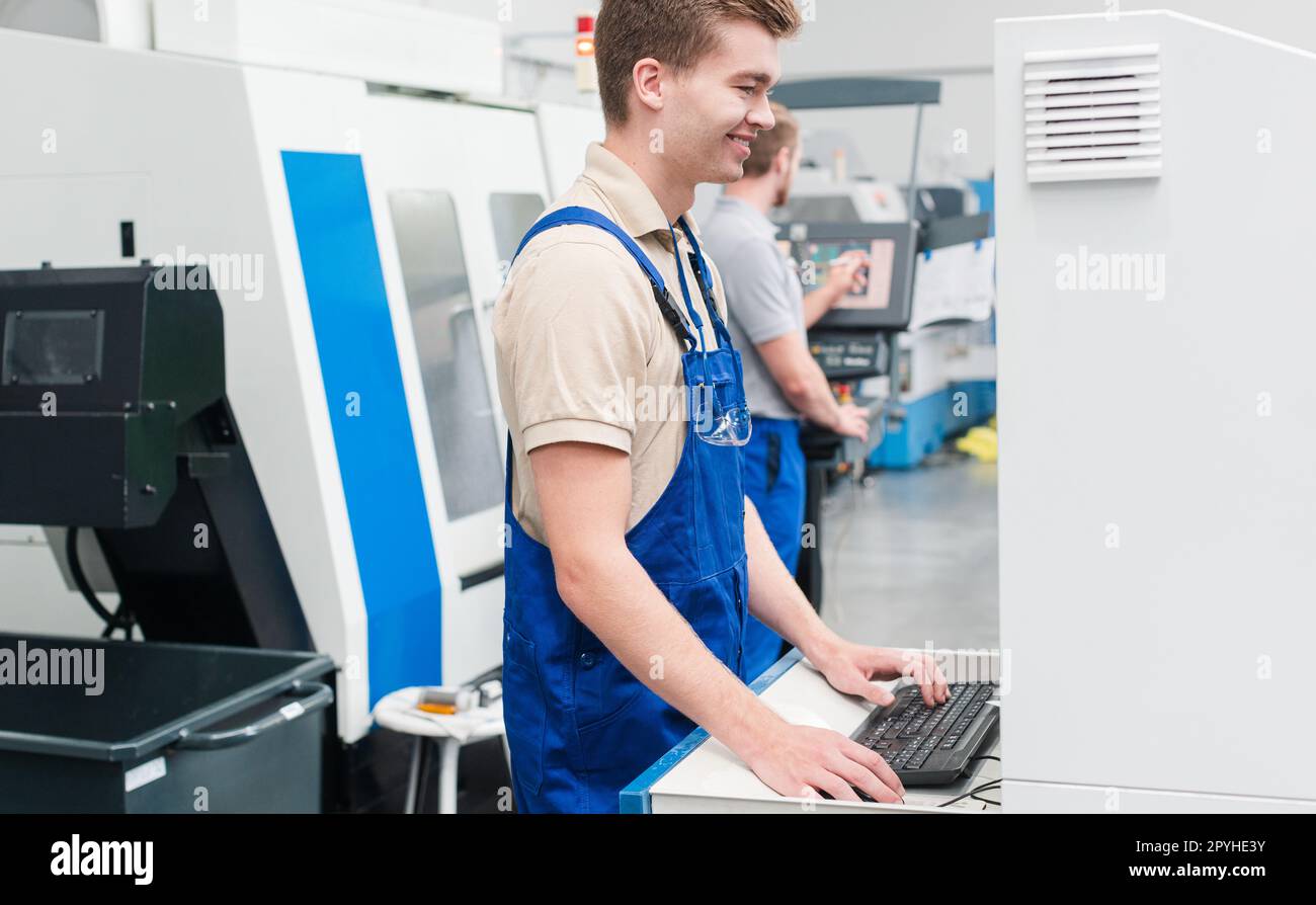 Worker using keyboard to enter data into a machine on factory floor ...