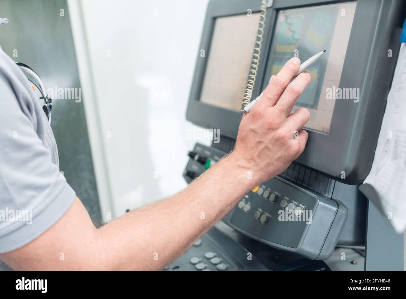 Worker entering data on screen of a modern machine tool in factory ...