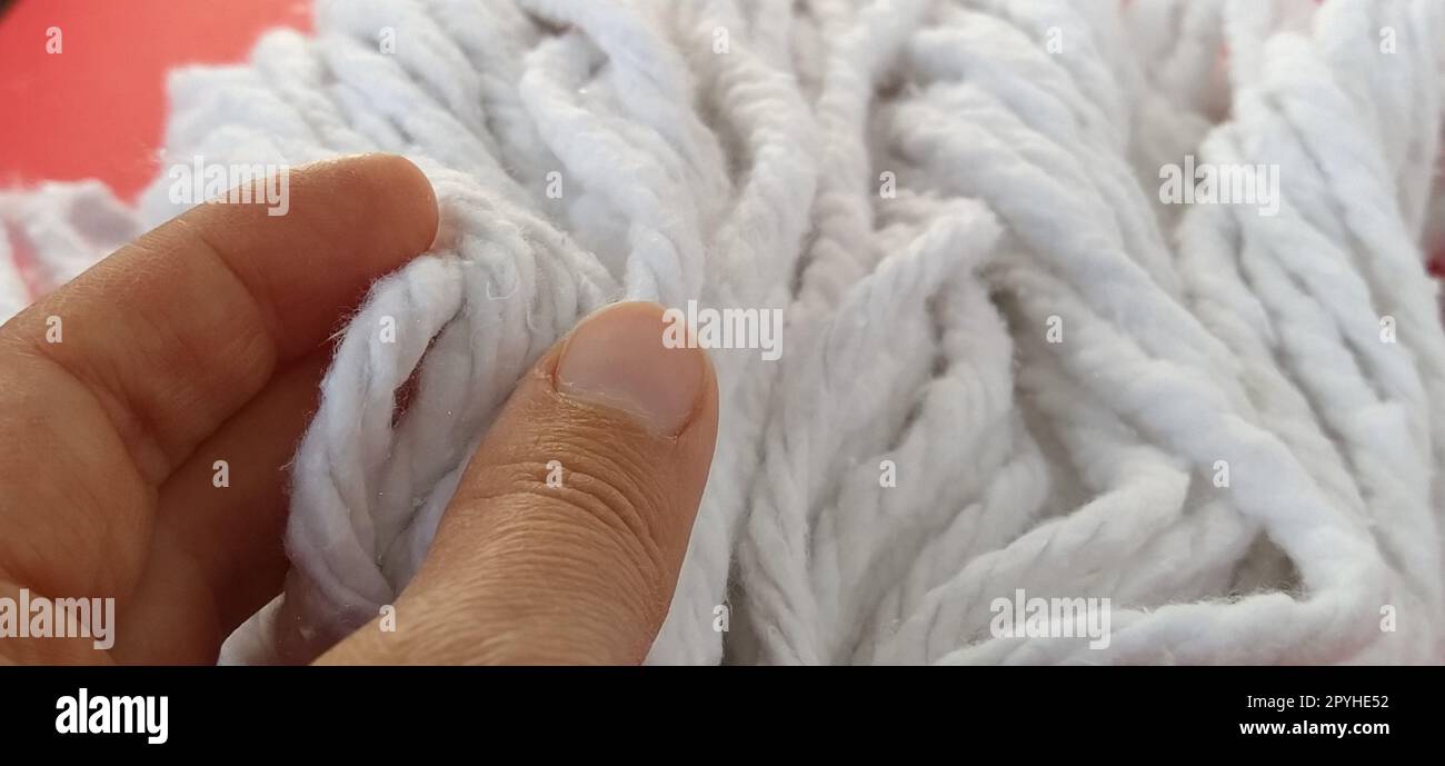 A woman's hand touches the cotton threads of the mop head. Choosing a ...
