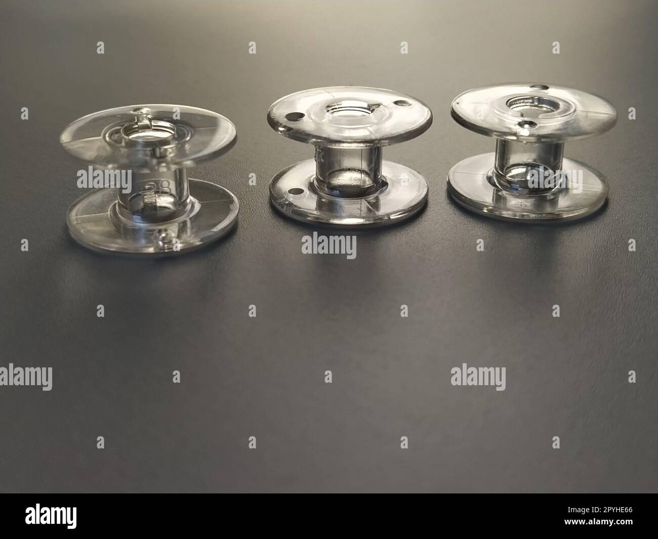 Three transparent plastic sewing machine bobbins. Textile industry ...