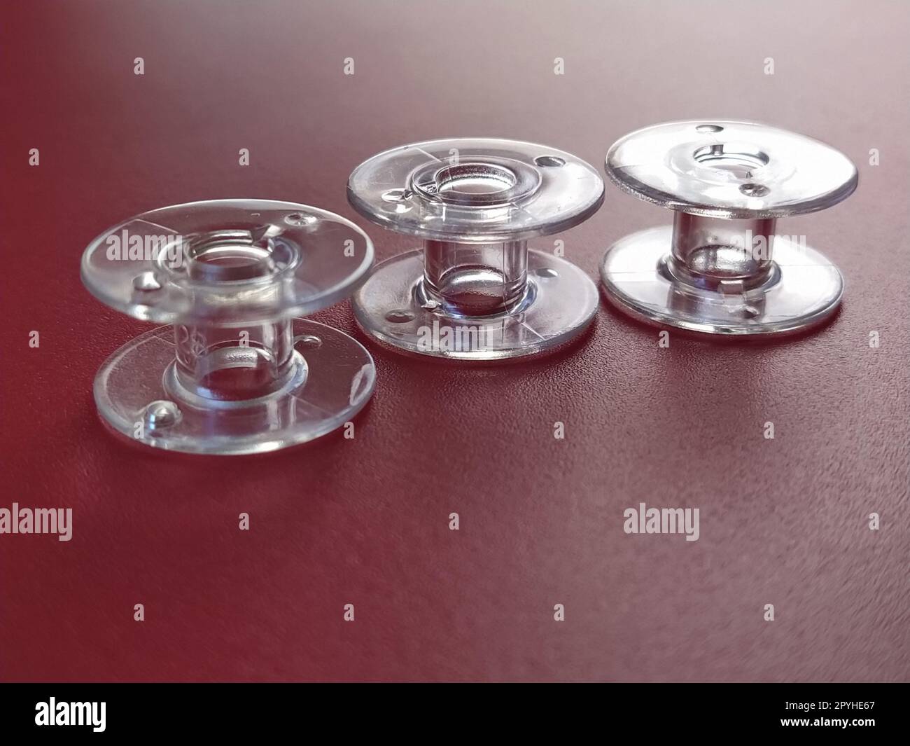 Three transparent plastic sewing machine bobbins. Textile industry ...