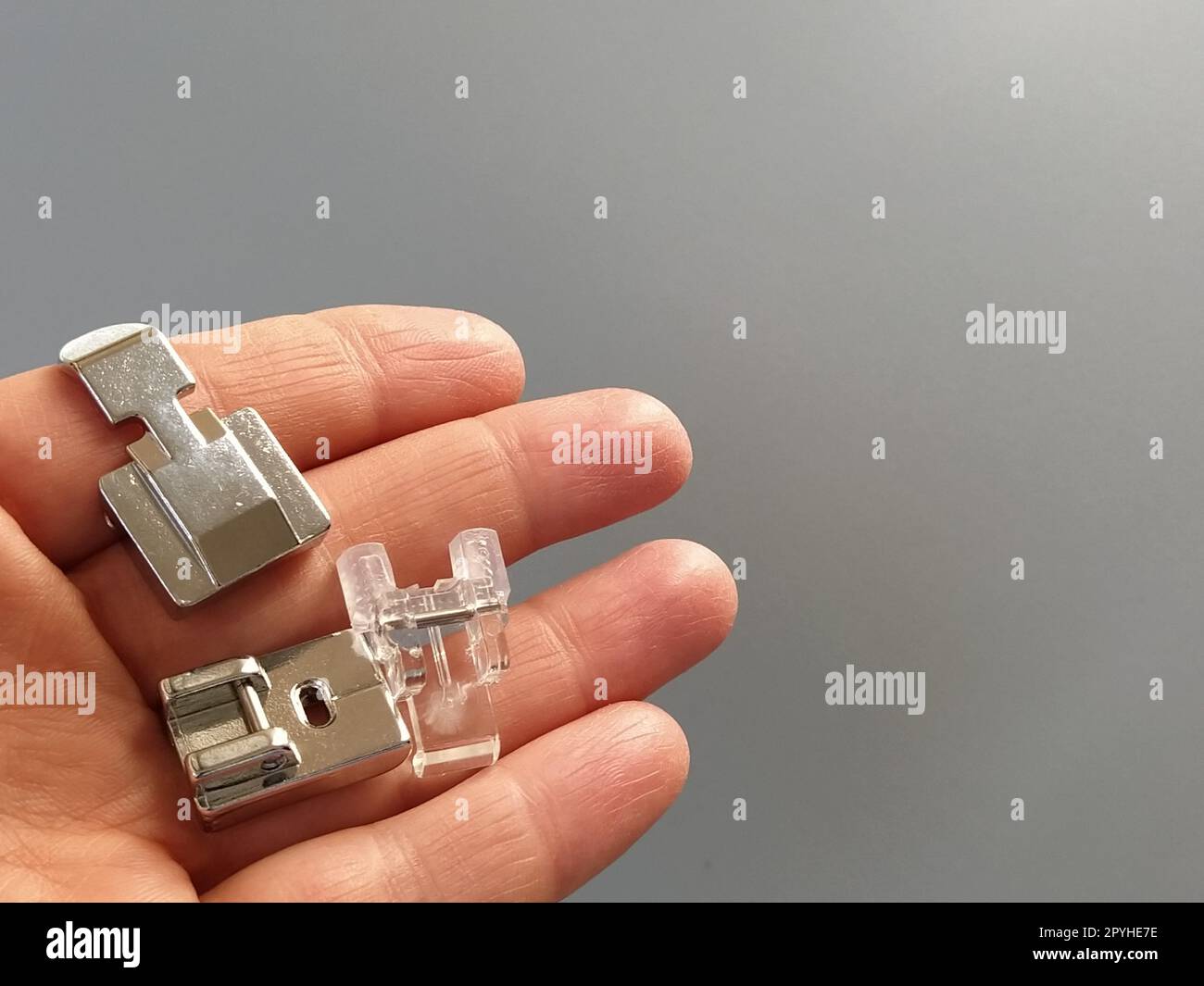 A set of feet for an electric sewing machine in a female hand. Gray ...