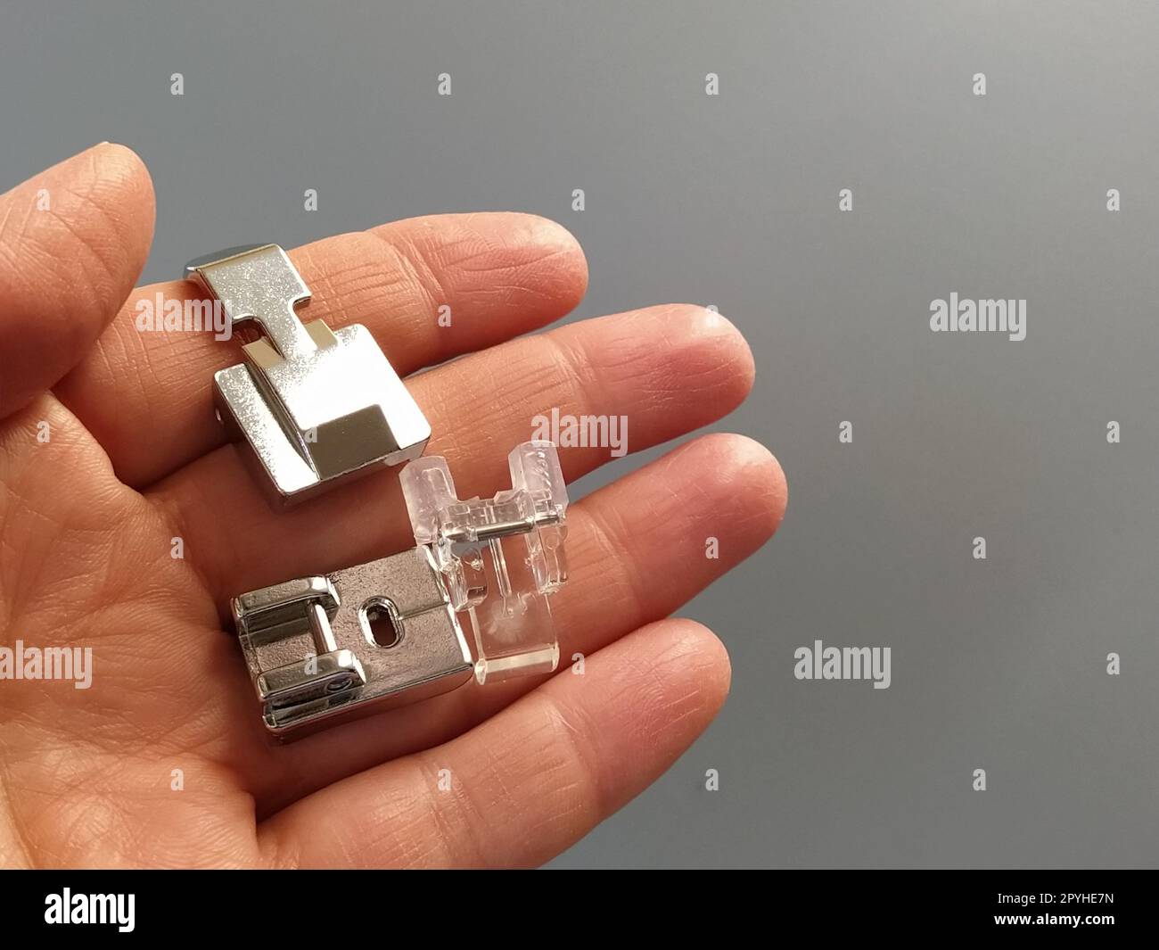 A set of feet for an electric sewing machine in a female hand. Gray ...