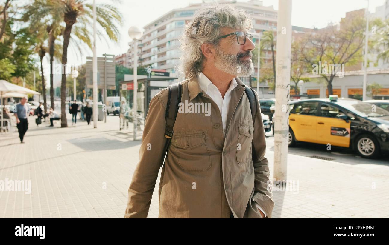Middle-aged man walking down the street with backpack Stock Photo - Alamy