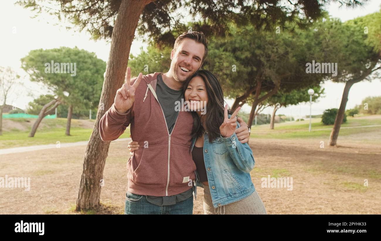 Close up, laughing couple hugging each other while standing in the park ...