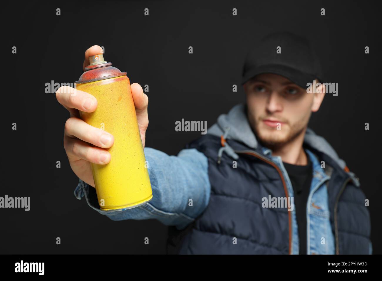 Handsome man holding used spray paint against black background Stock ...