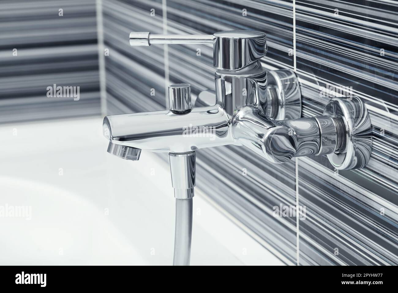 Shiny bath water tap installed on black and white wall Stock Photo - Alamy