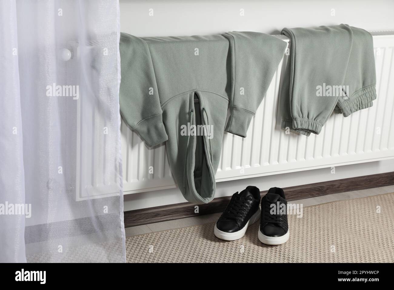 Heating radiator with clothes and shoes in room Stock Photo - Alamy