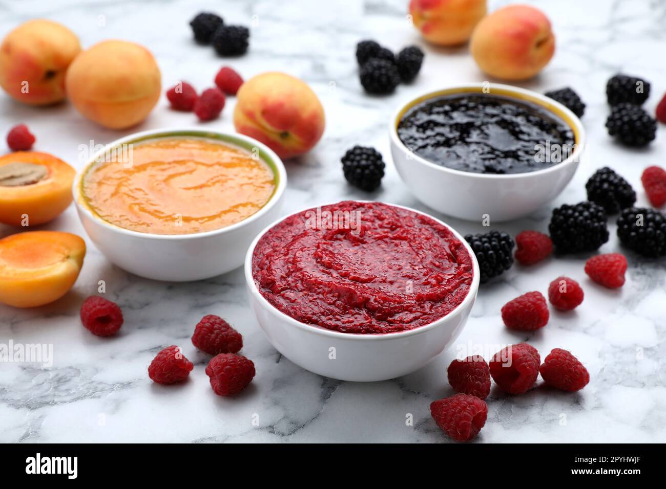 Different puree in bowls and fresh ingredients on white marble table ...