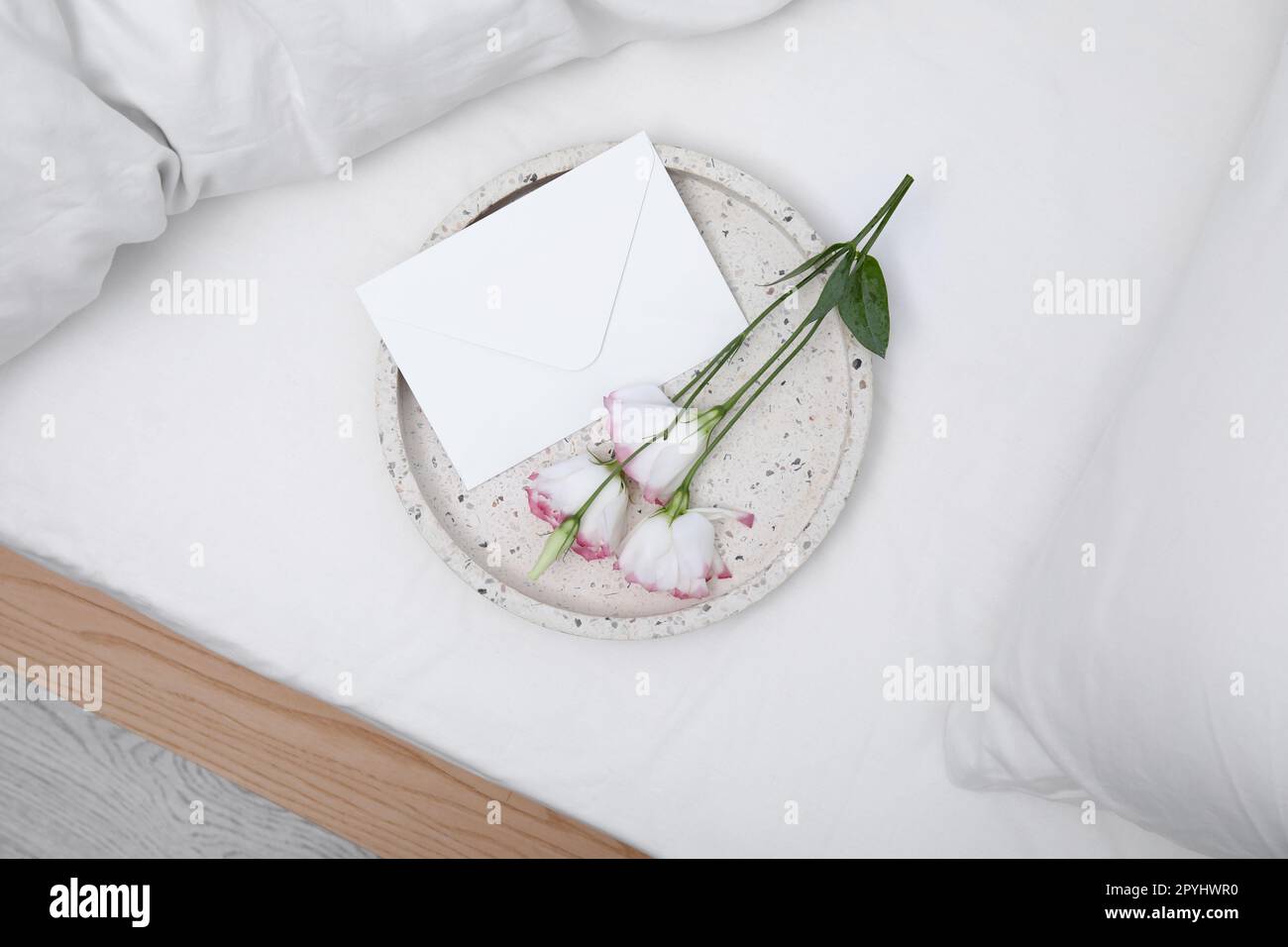 Tray with beautiful flowers and envelope on white bed, top view Stock ...