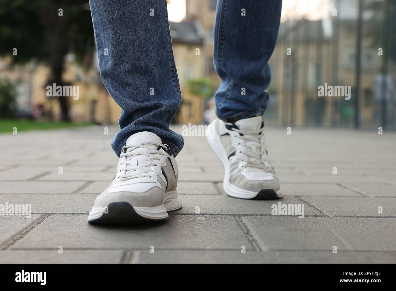 Man in jeans and sneakers walking on city street, closeup Stock Photo ...