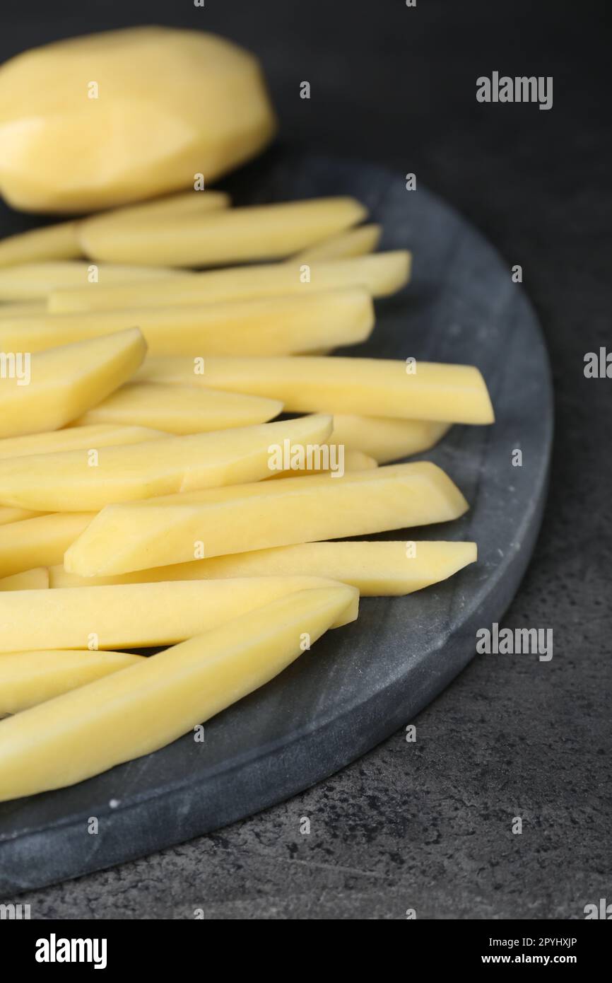 Whole and cut raw potatoes on grey table, closeup. Cooking delicious ...