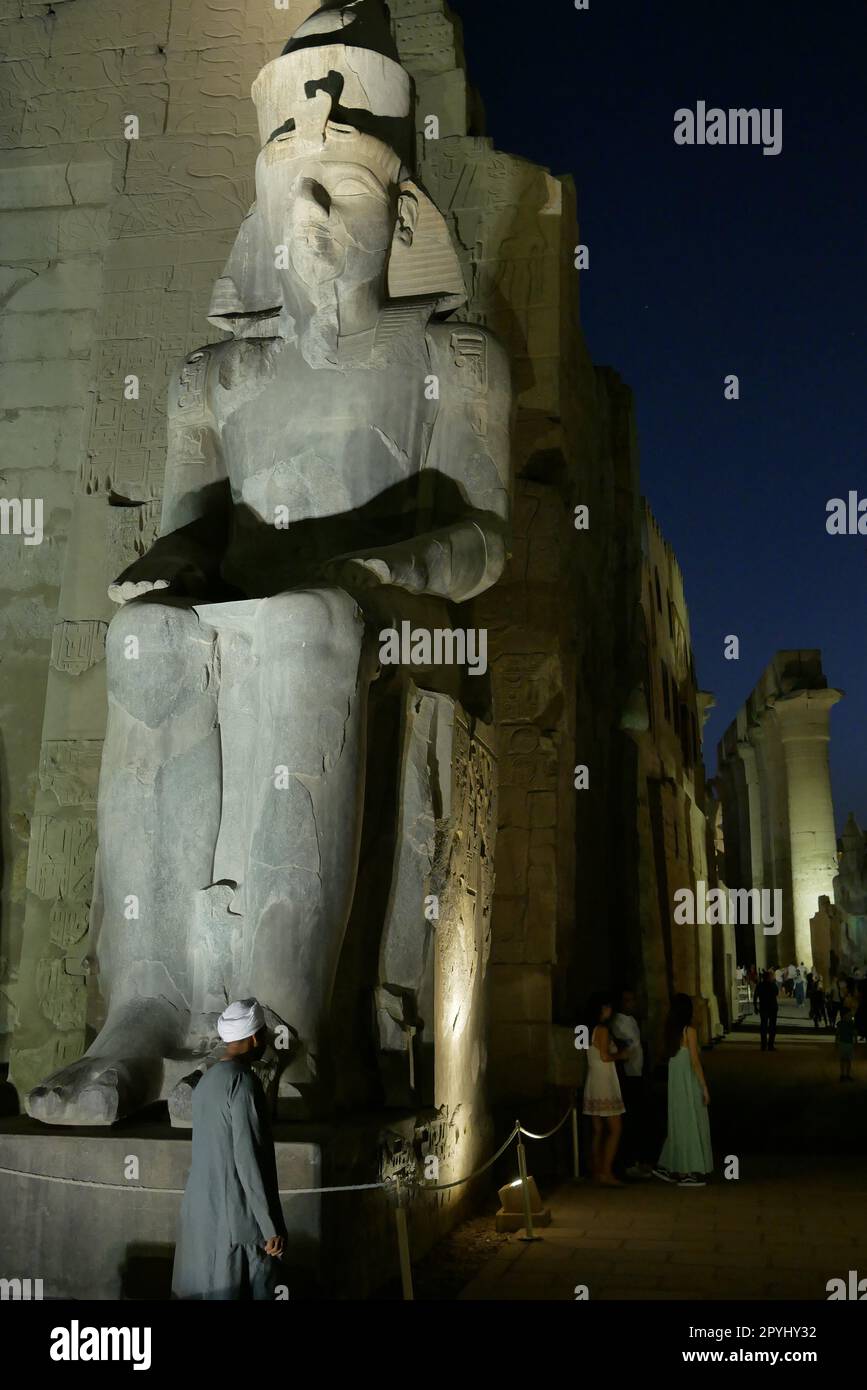Caretaker standing below the statue of pharaoh Ramses in Luxor Temple ...
