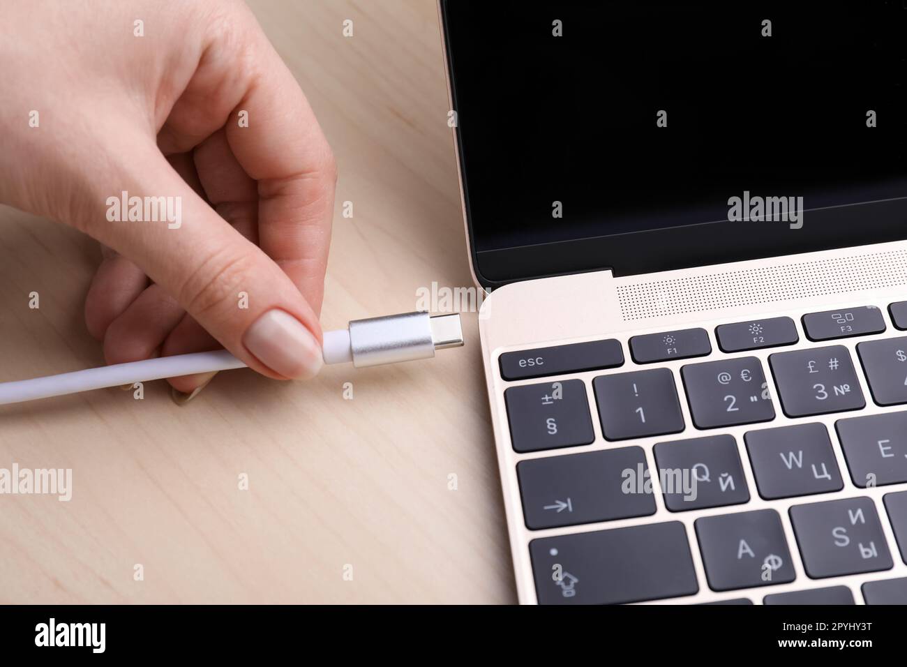 Woman plugging USB cable with type C connector into laptop port on ...