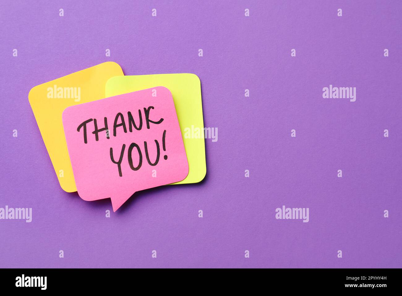 Pink paper note with phrase Thank You on purple background, top view ...