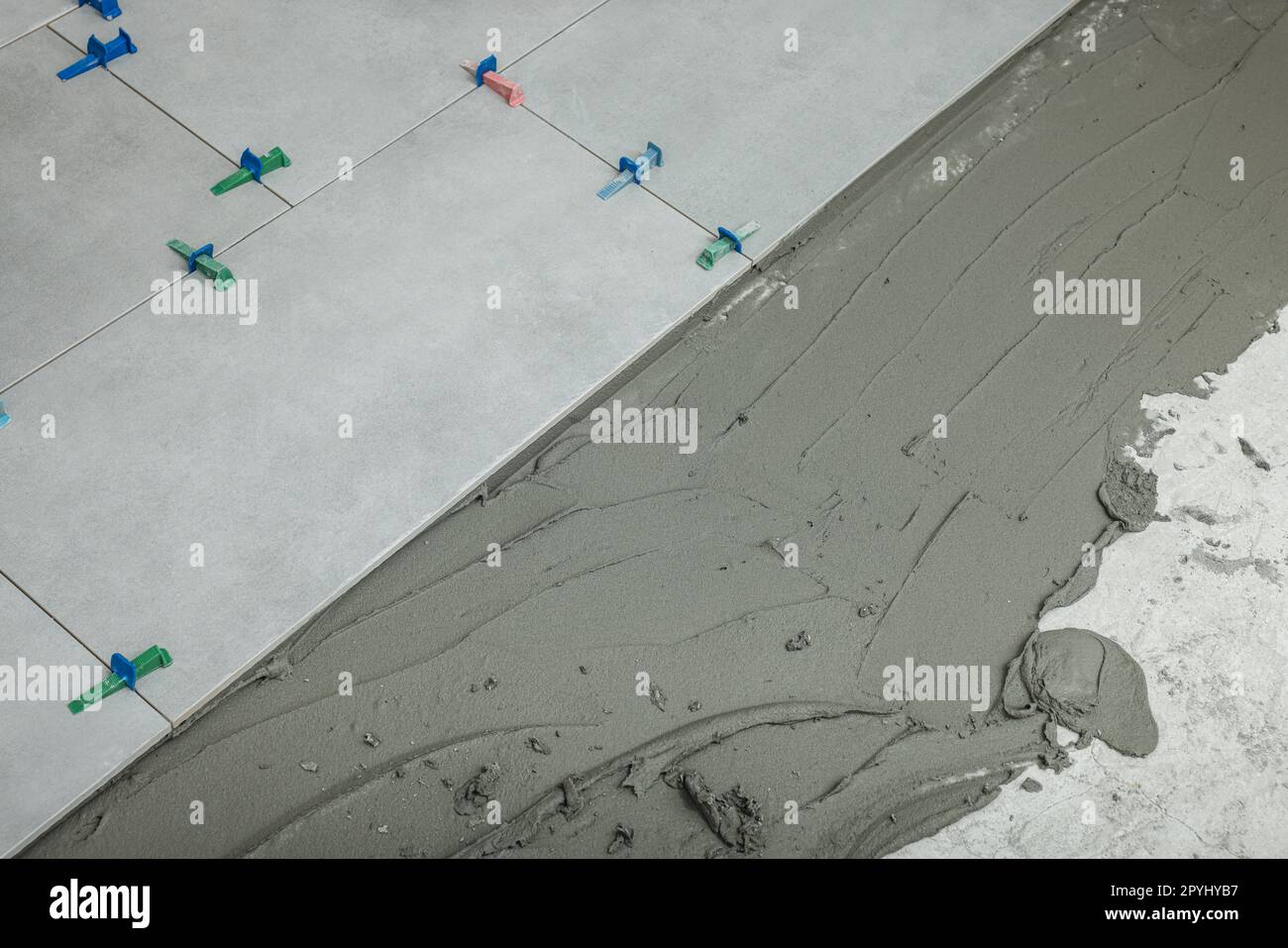 Beautiful tiles with wedges and adhesive mix on floor Stock Photo - Alamy