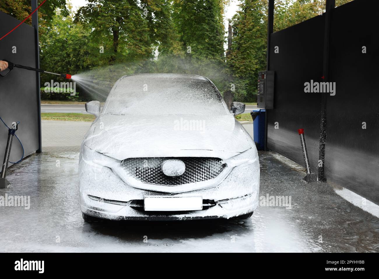 Man washing auto with high pressure water jet at car wash, closeup ...