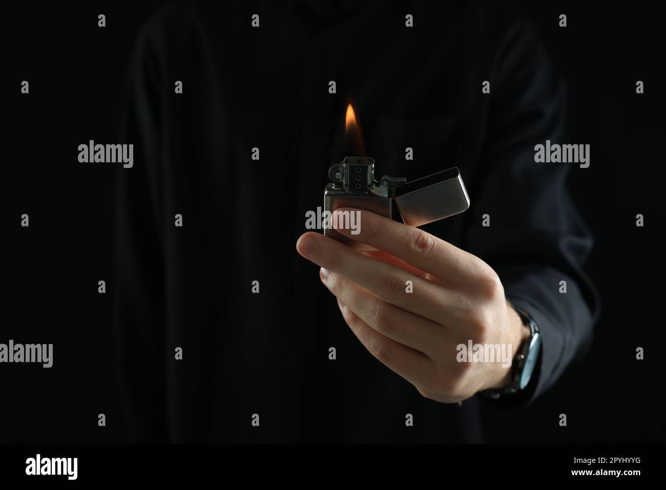 Man holding lighter with burning flame on black background, closeup ...