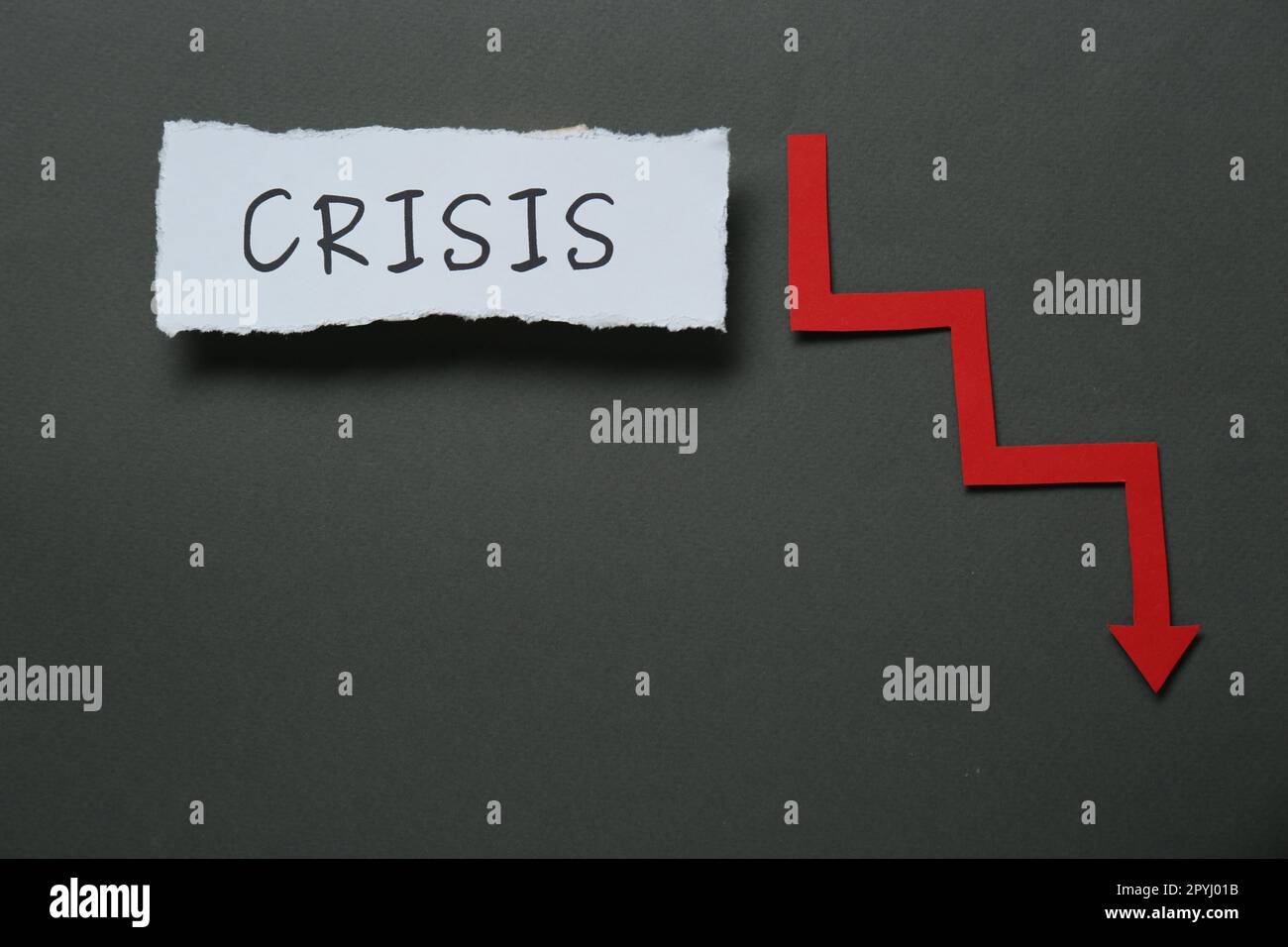 Paper piece with word Crisis and descending red arrow on black ...