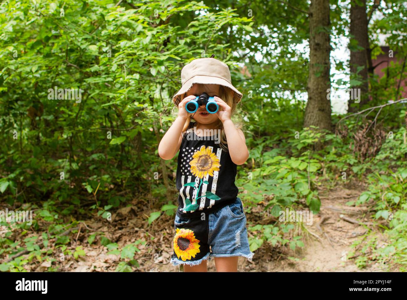 Little girl is looking through binoculars during hiking. Exploring ...
