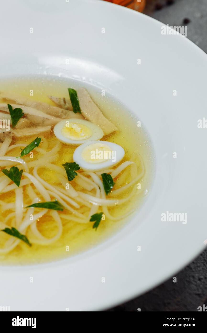 Low-fat chicken broth with a half cooked egg and parsley in a glass ...