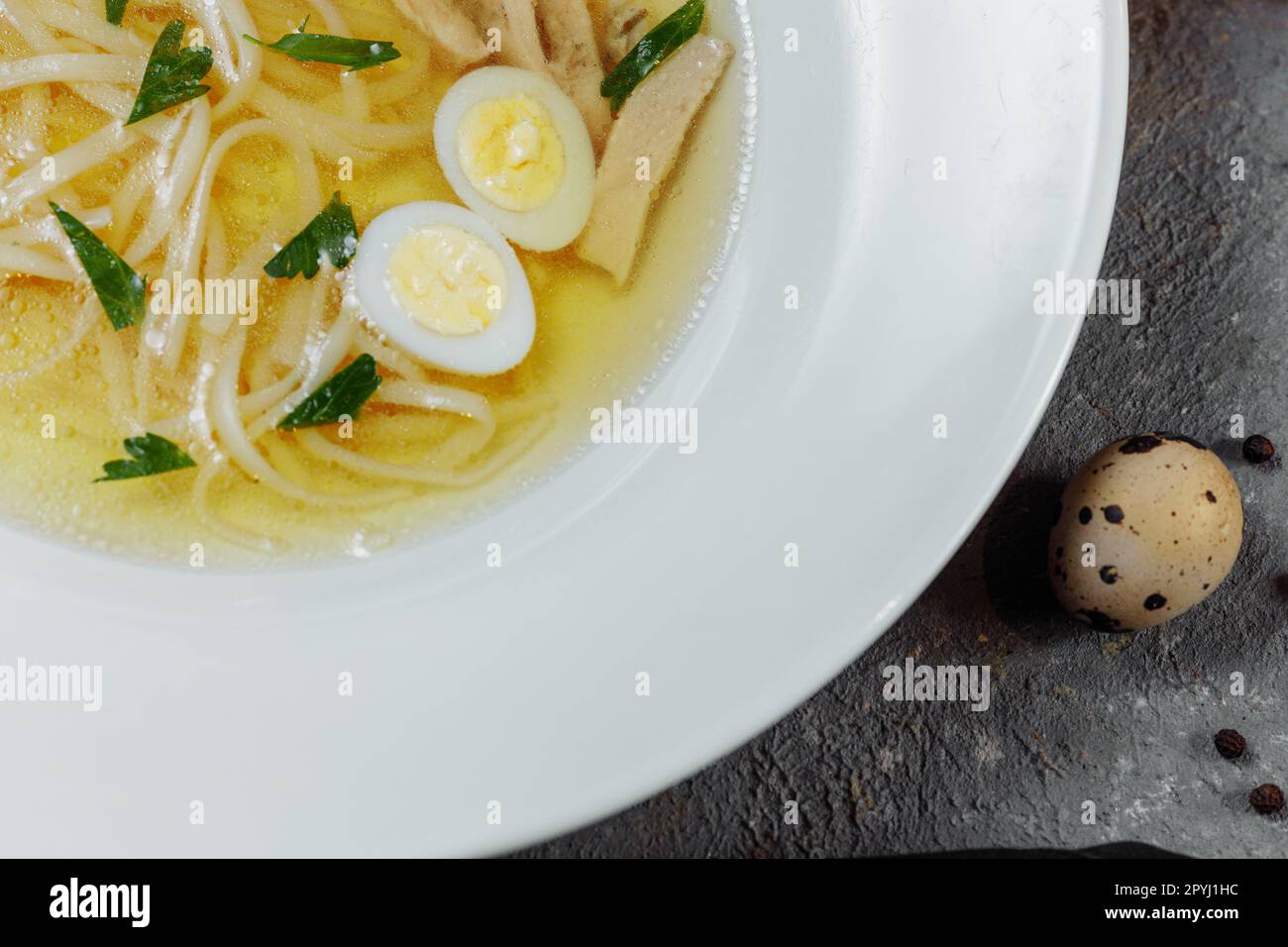 Low-fat chicken broth with a half cooked egg and parsley in a glass ...