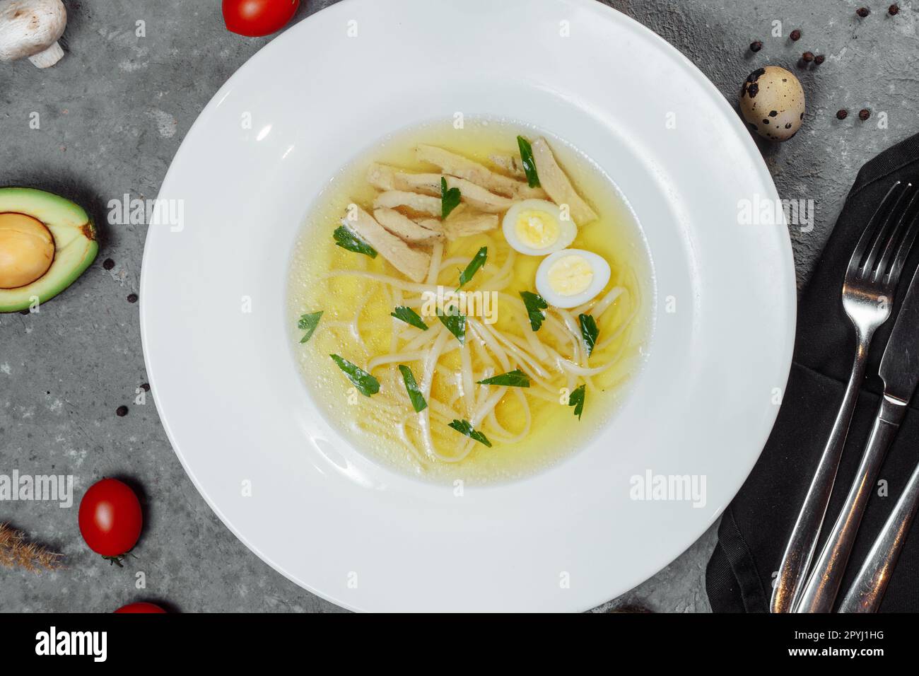Low-fat chicken broth with a half cooked egg and parsley in a glass ...
