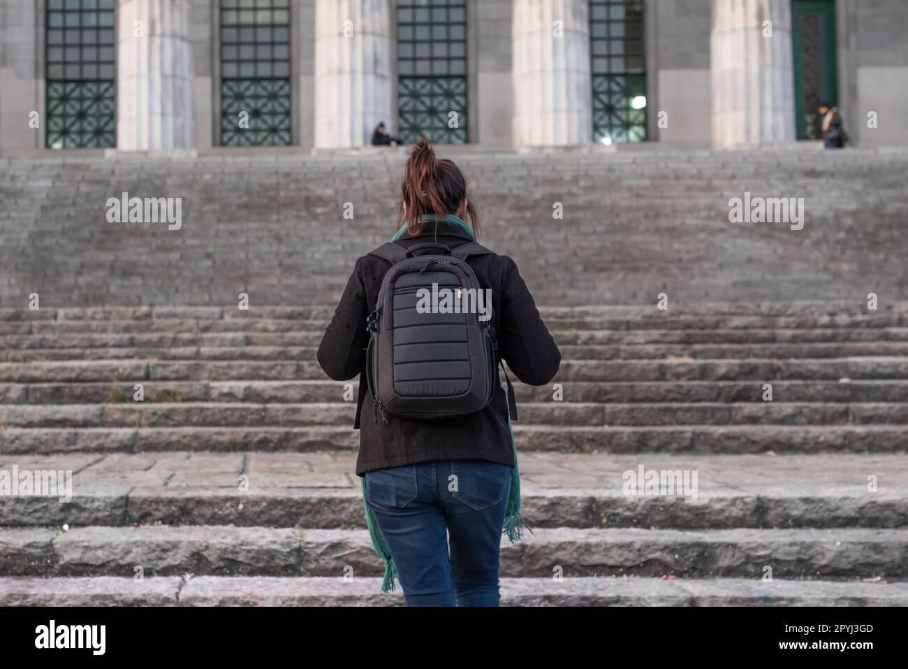 Portrait of a female student on her back walking up the stairways of ...