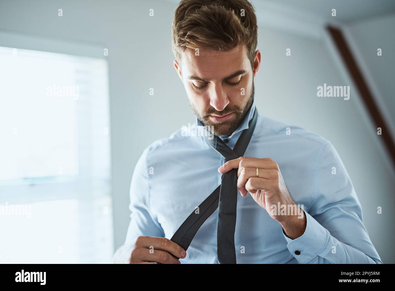 There is a method. a handsome young man dressing himself at home Stock ...