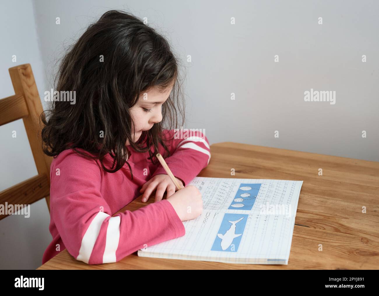 young girl practicing her writing at the table Stock Photo - Alamy