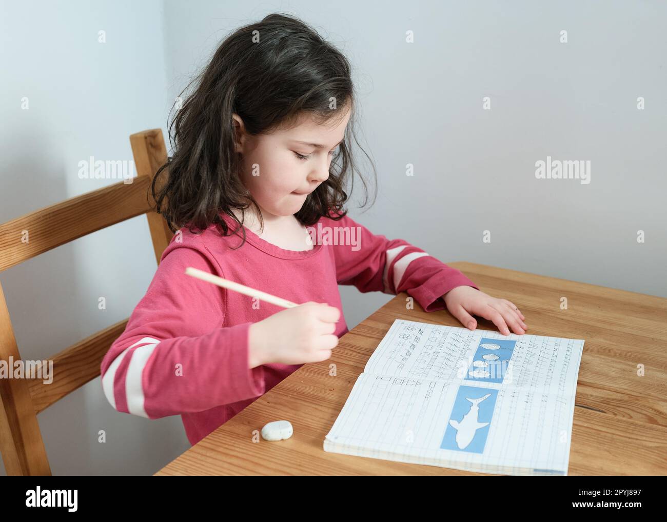 young girl practicing her writing at the table Stock Photo - Alamy