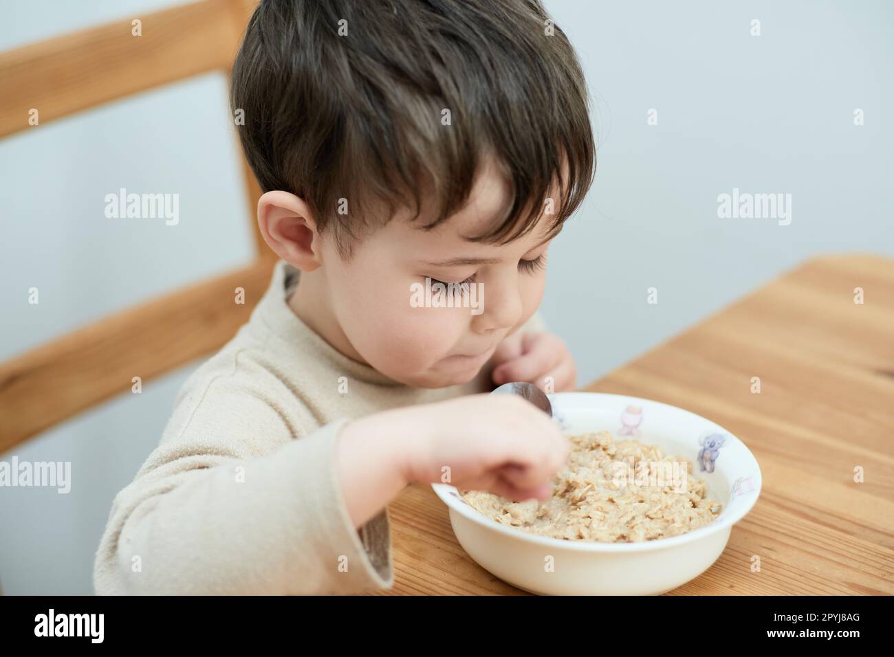 little boy eating oatmeal for breakfast in the kitchen Stock Photo - Alamy