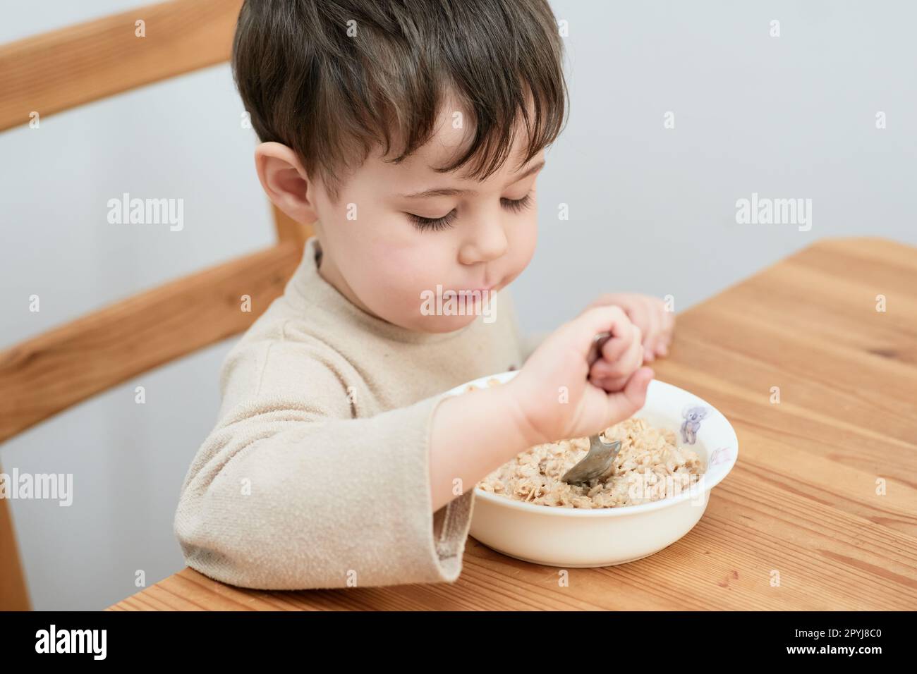 little boy eating oatmeal for breakfast in the kitchen Stock Photo - Alamy