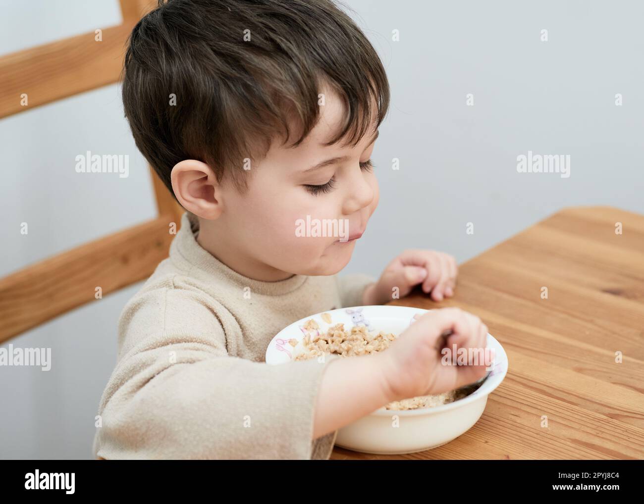 little boy eating oatmeal for breakfast in the kitchen Stock Photo - Alamy