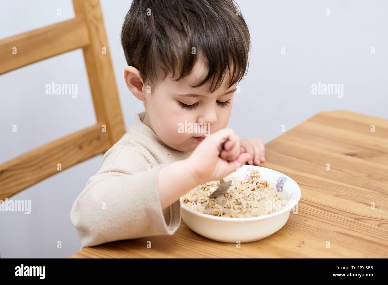 little boy eating oatmeal for breakfast in the kitchen Stock Photo - Alamy