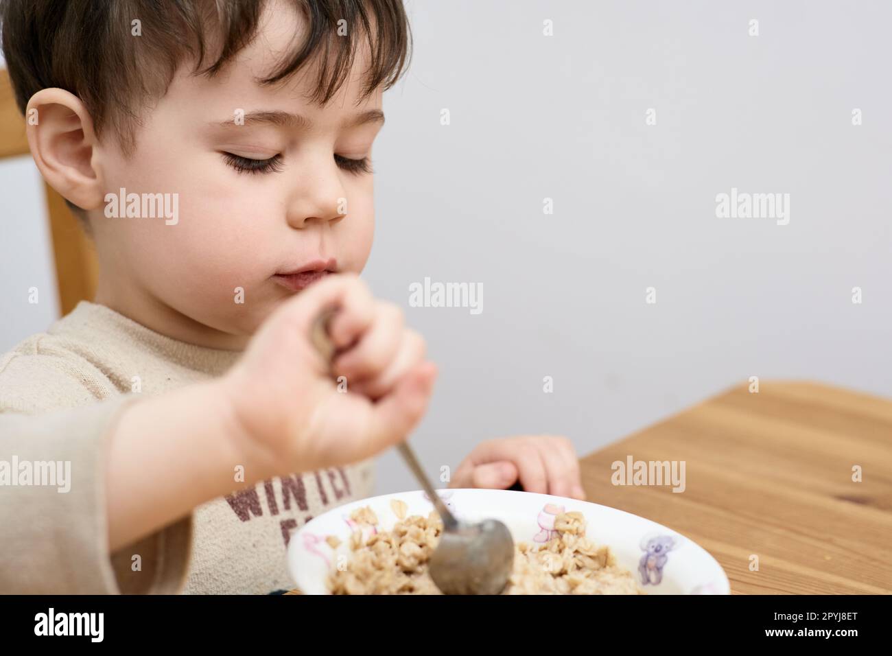 little boy eating oatmeal for breakfast in the kitchen Stock Photo - Alamy
