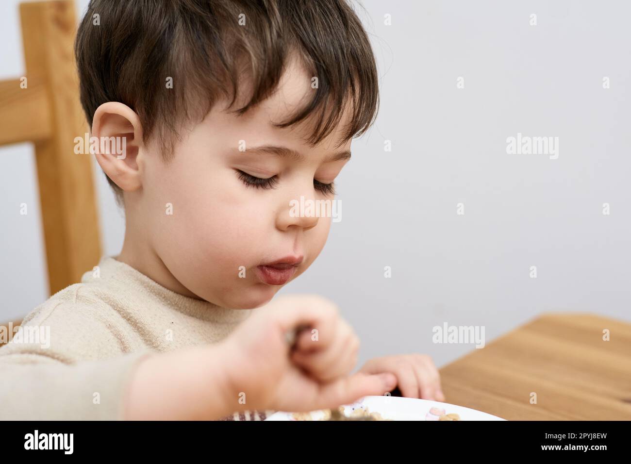 little boy eating oatmeal for breakfast in the kitchen Stock Photo - Alamy