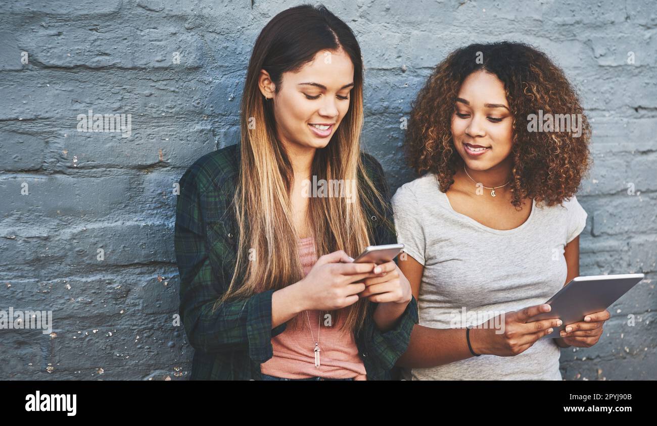 How millennials stay entertained. two young women standing outdoors and ...