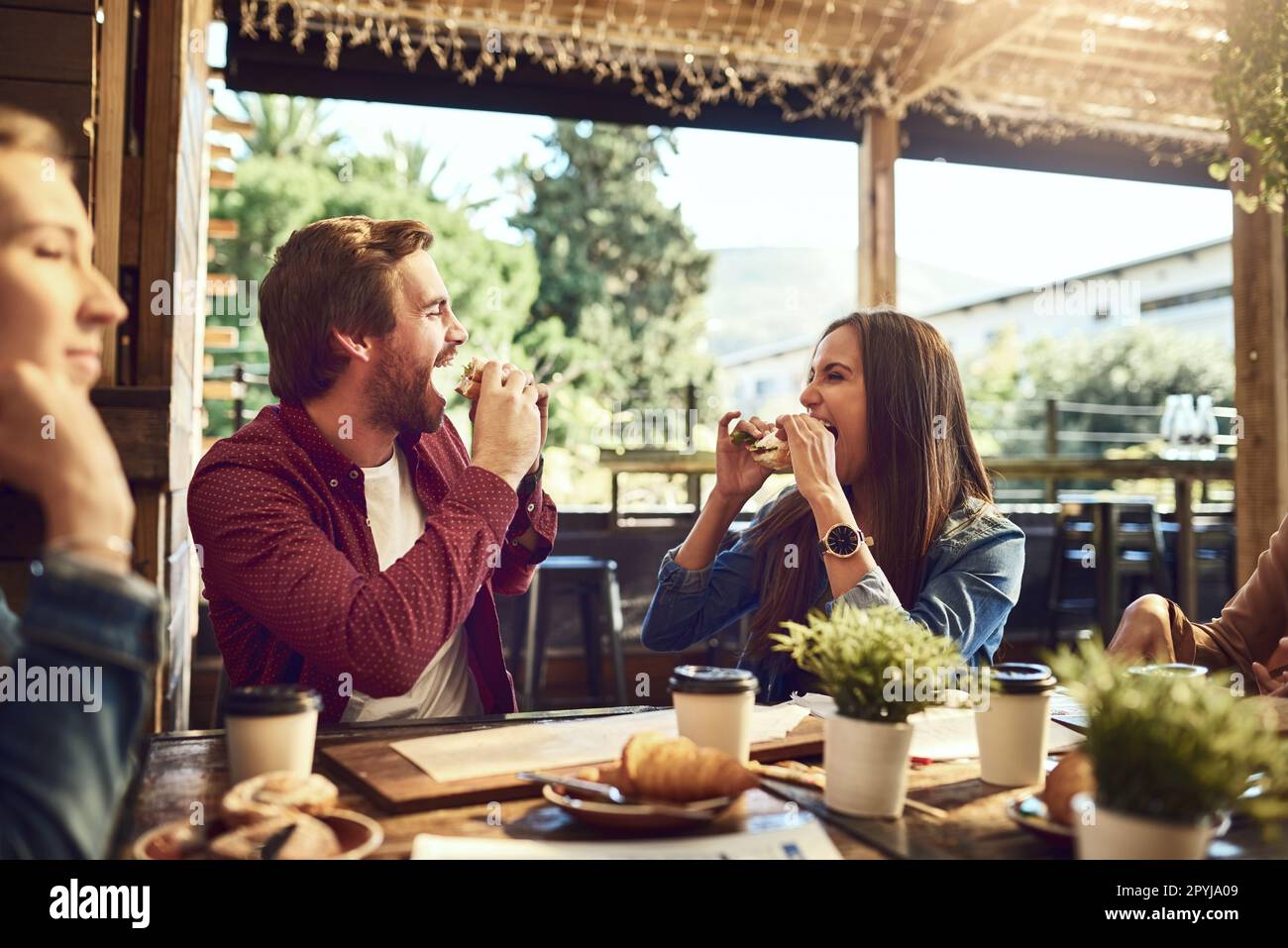 Take your biggest bite. an affectionate young couple biting into their ...
