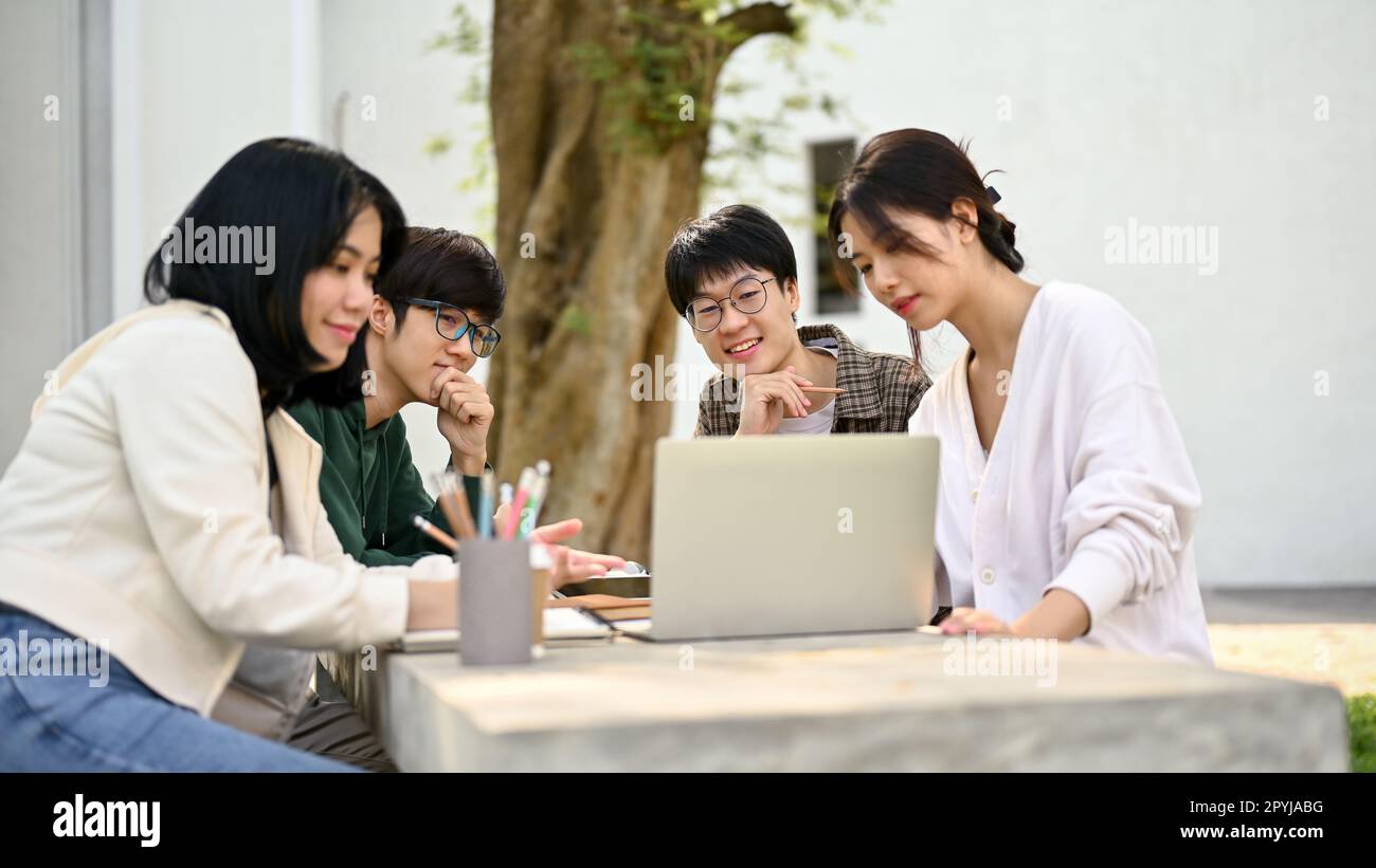 Group of happy Asian college students looking at a laptop screen ...