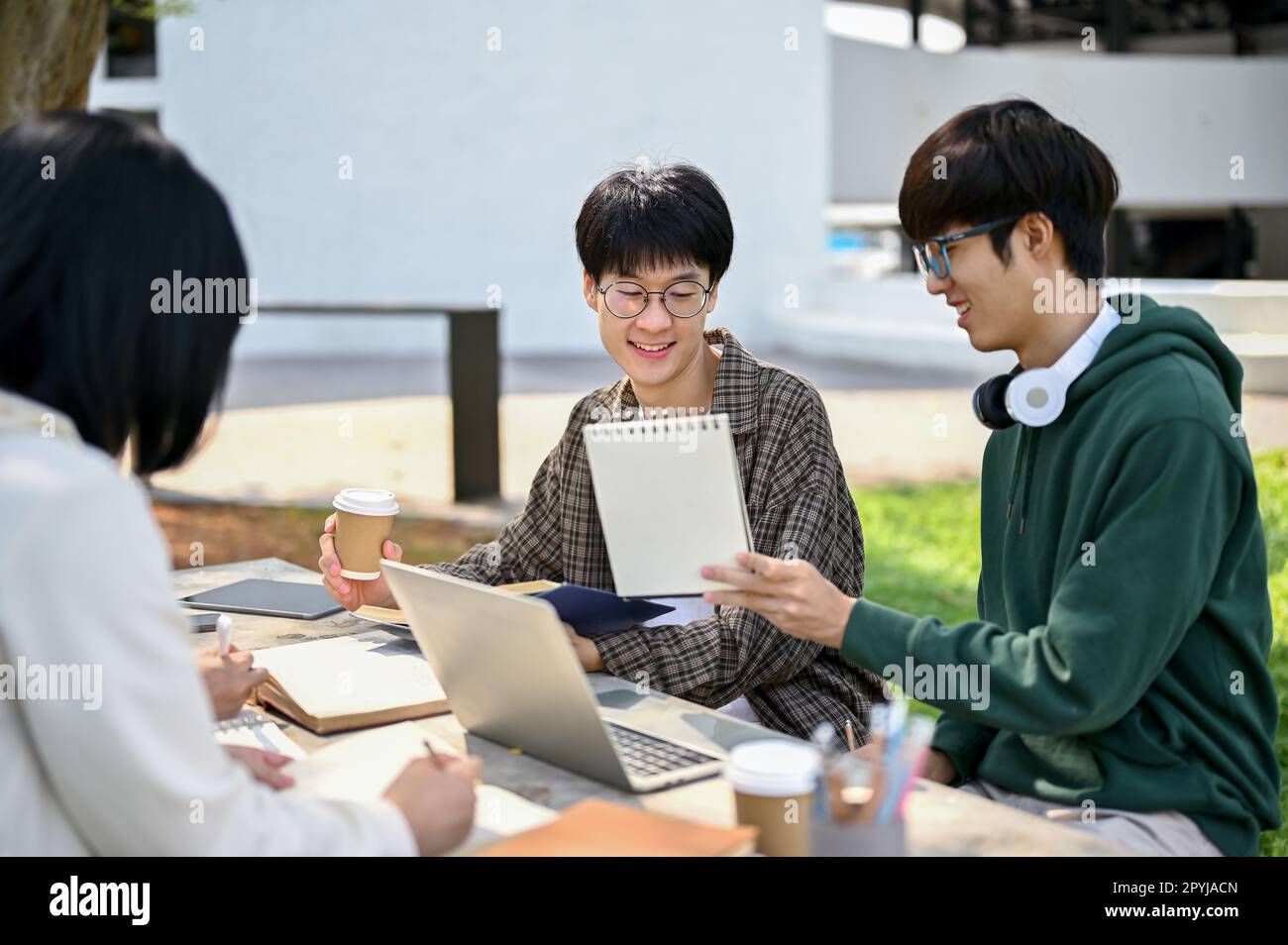 Smart young Asian male college student is tutoring math to his friends ...