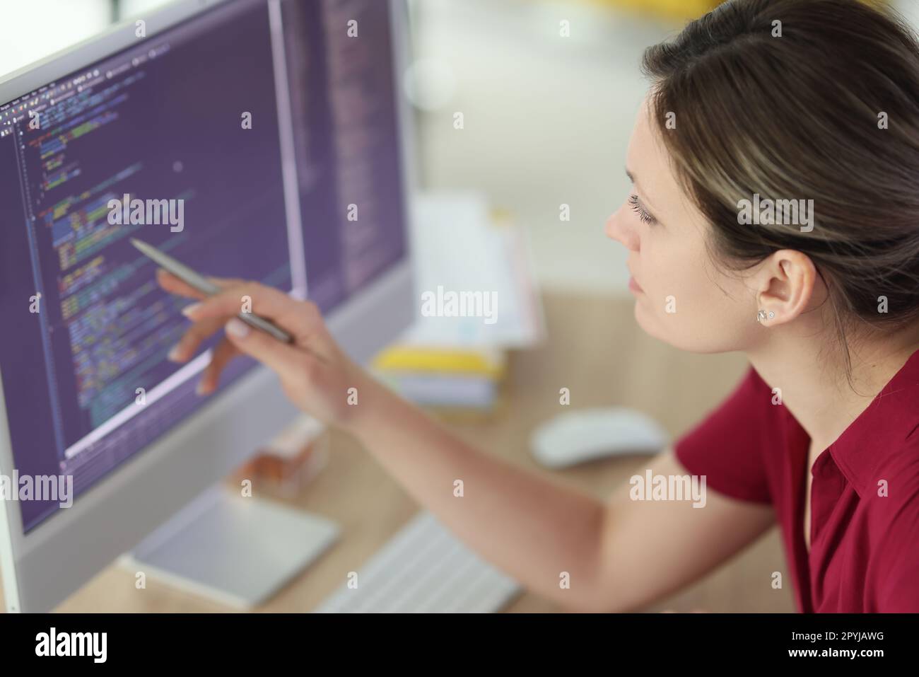 Woman checks code pointing pen to screen of computer Stock Photo - Alamy