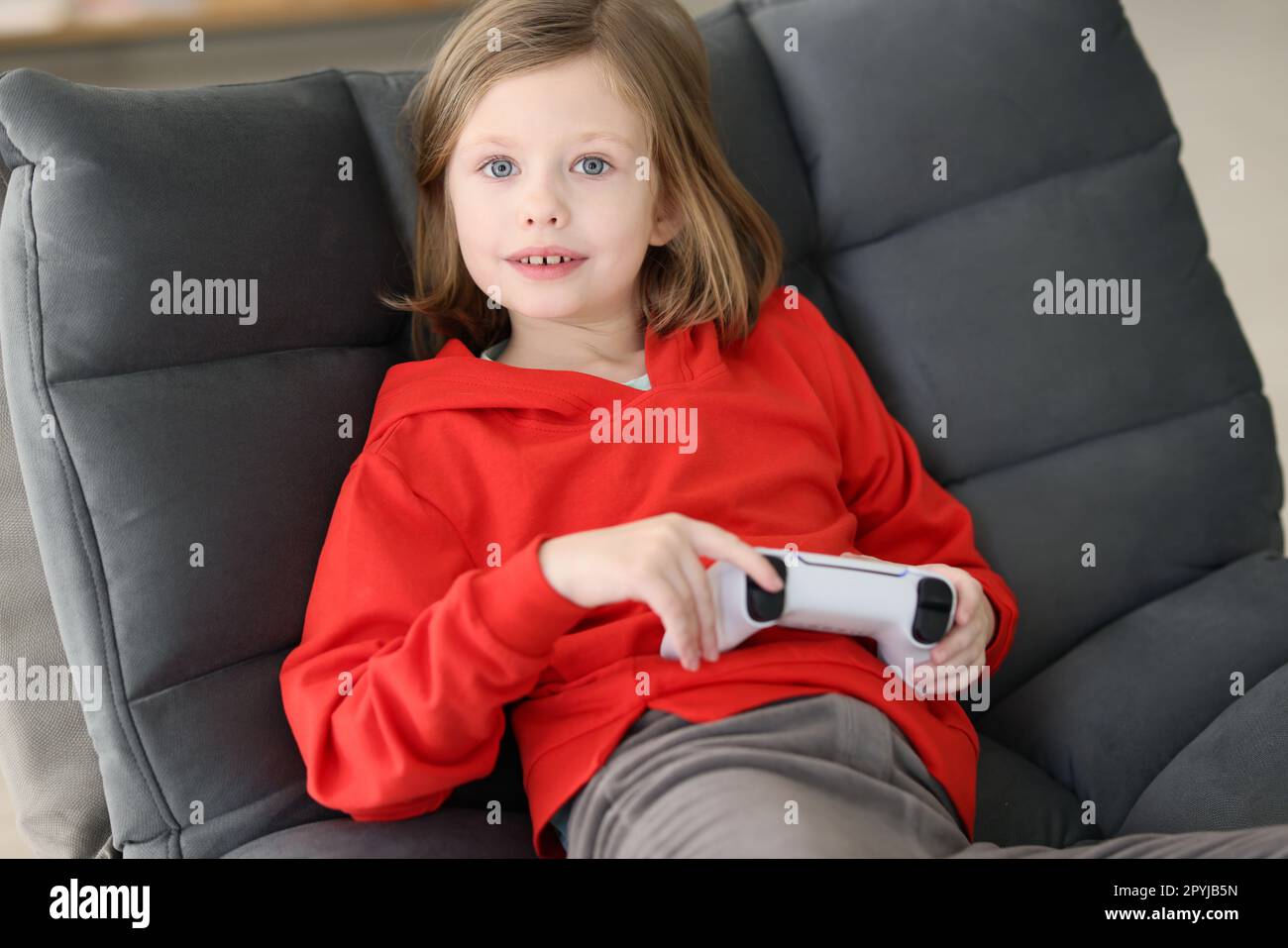 Cute little girl looks in camera holding gaming console Stock Photo - Alamy