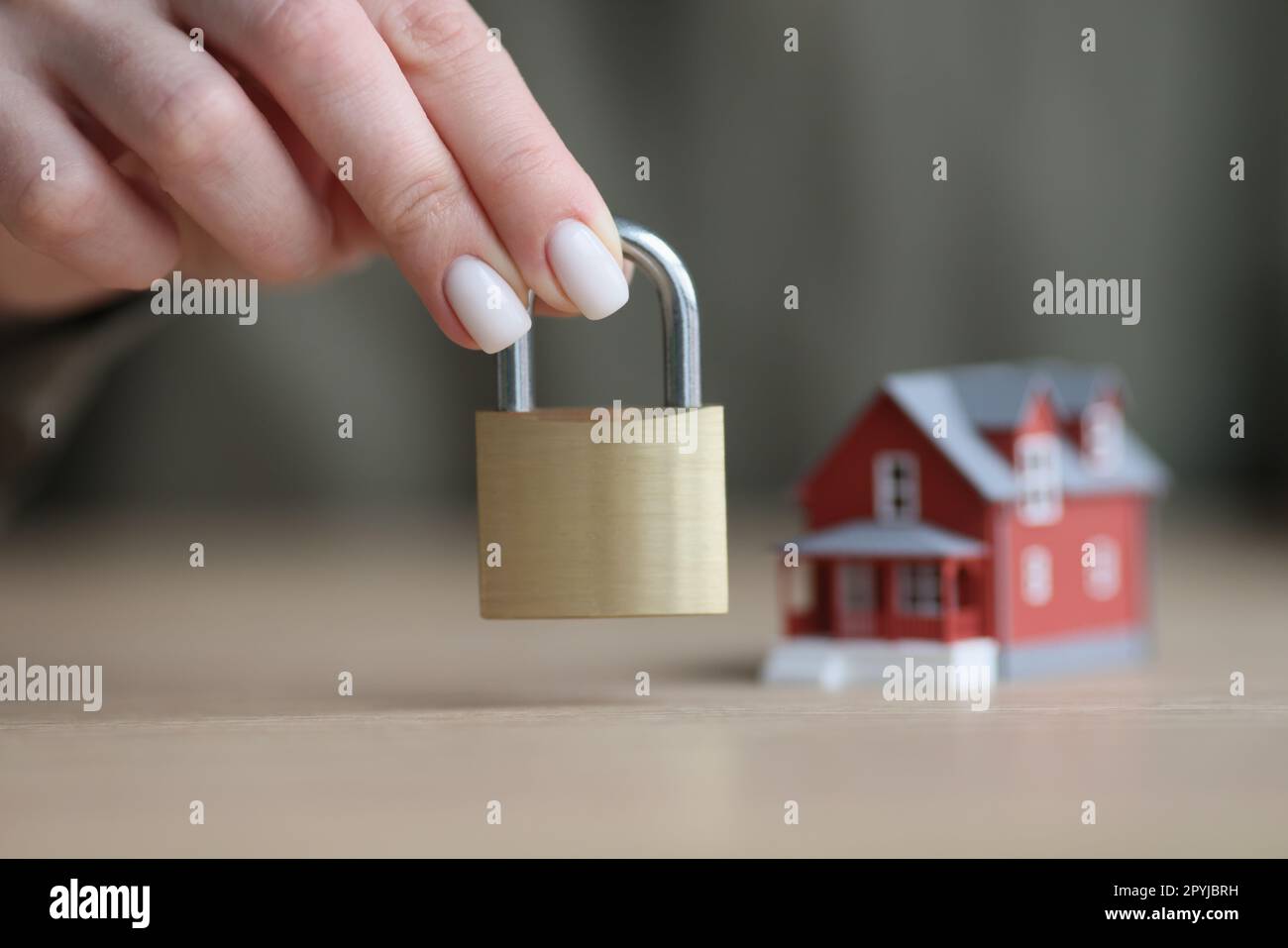 Hand of woman holding iron door lock against model of house Stock Photo ...