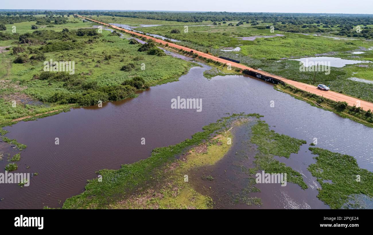 Aerial view of Transpantaneira dirt road with bridge beside a lagoon in ...